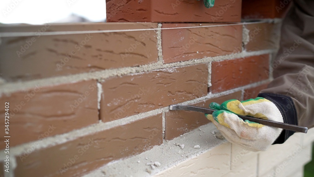 Worker wipes the seams in the brickwork. Worker rewrites a brick wall ...