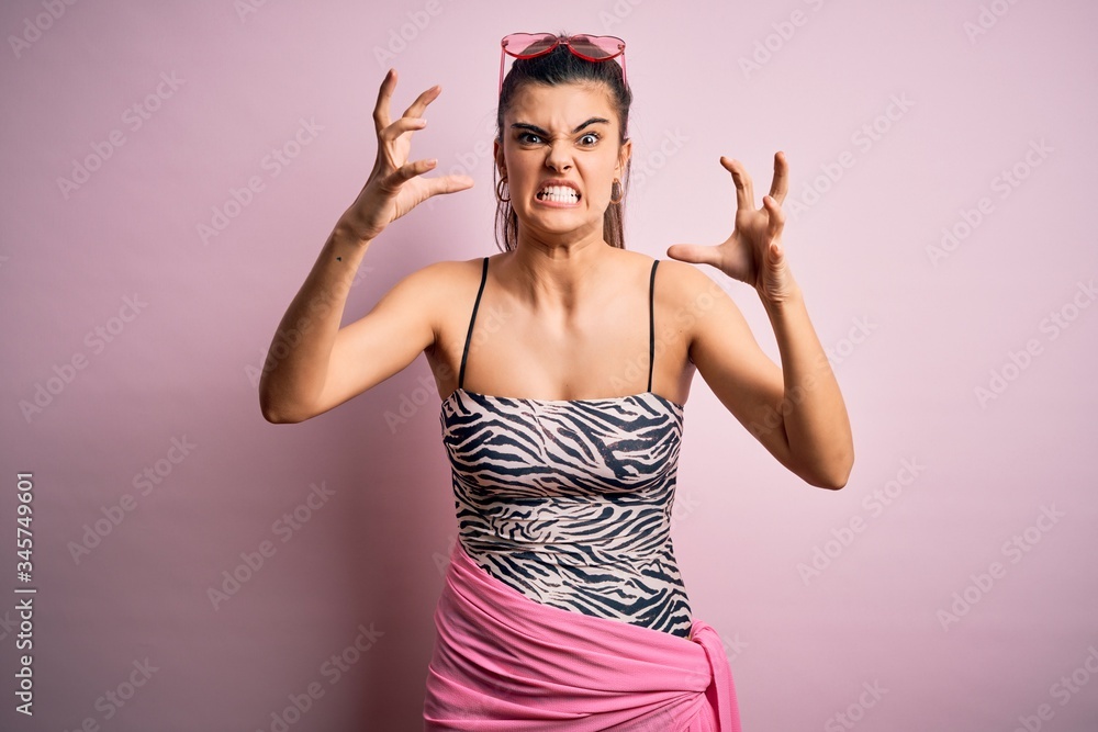 Young beautiful brunette woman on vacation wearing swimsuit over pink ...