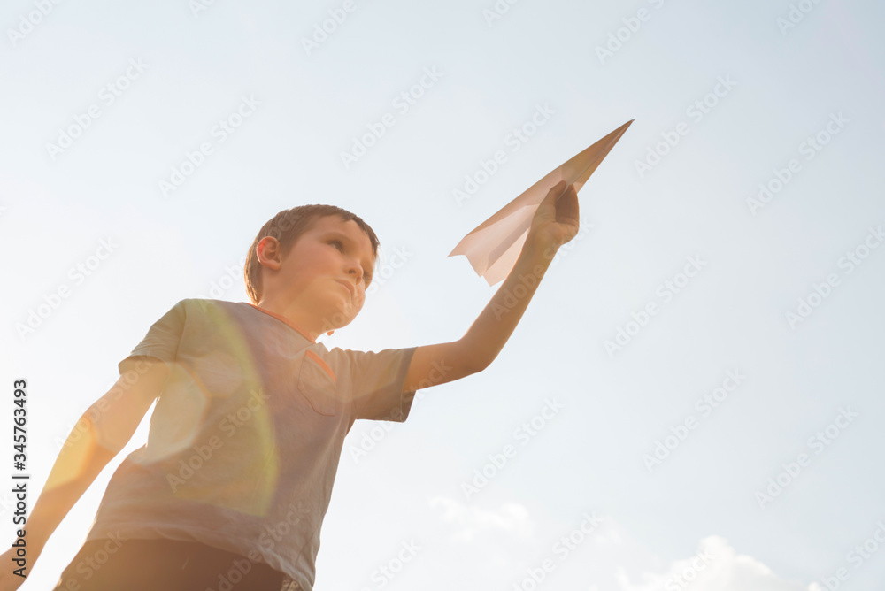 Little boy launches a paper plane into the air. Child launches a paper ...