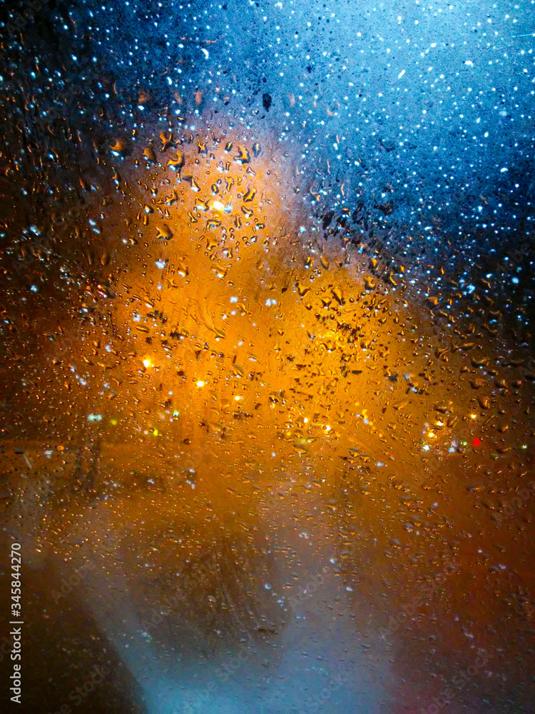 Drops of rain on window at night. Rainy and night city behind glass ...