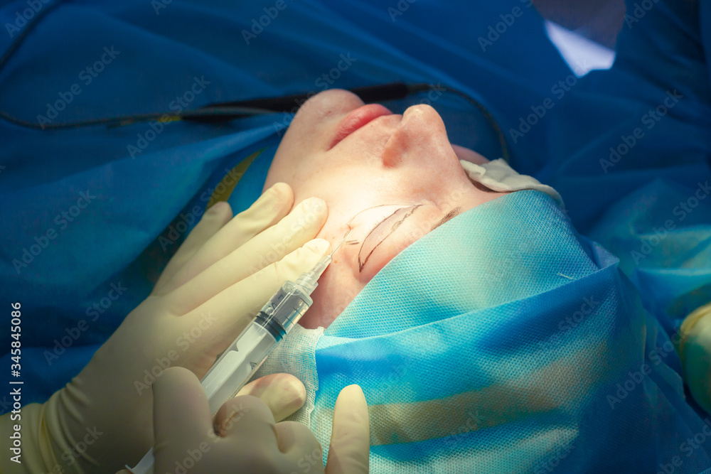 Surgeon inserts an injection into the lower eyelid of the patient ...