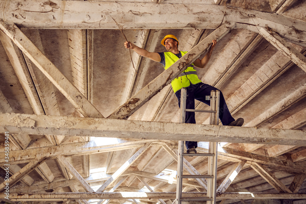 Construction site builder climbing on ladder and preparing to fix ...