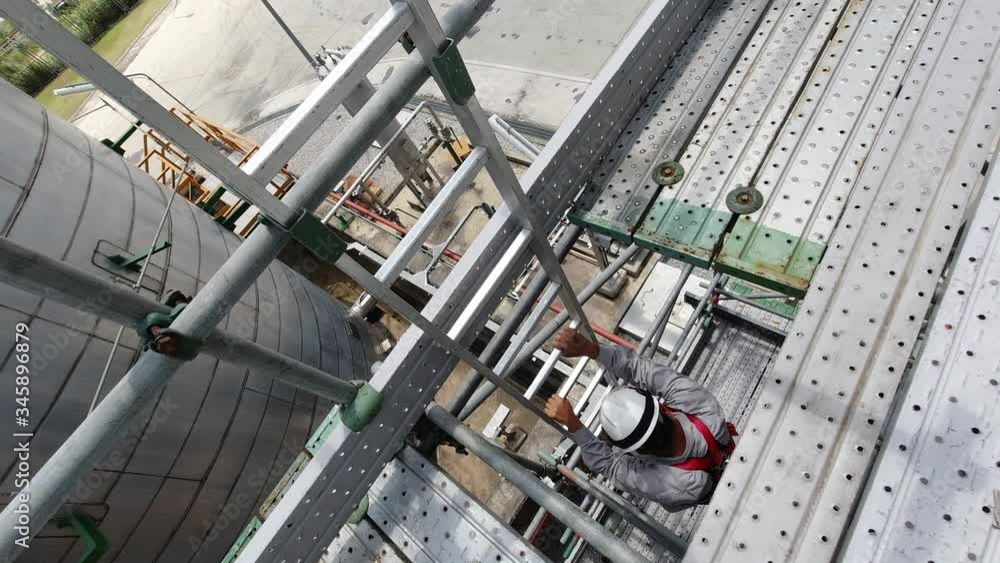 Stockvideo A worker wearing a safety belt climb on a ladder for working ...