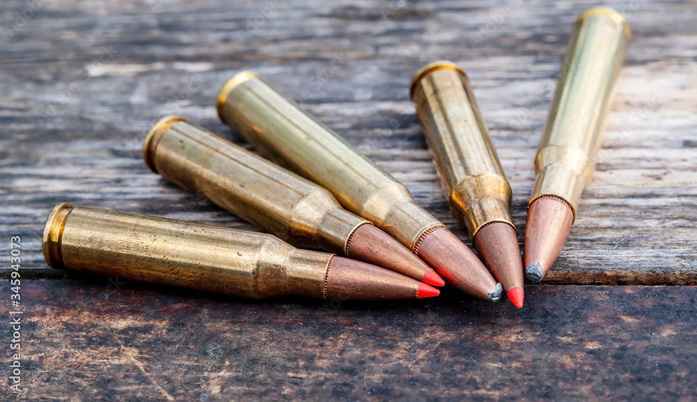 Five different caliber rifle bullets together on a wooden background ...