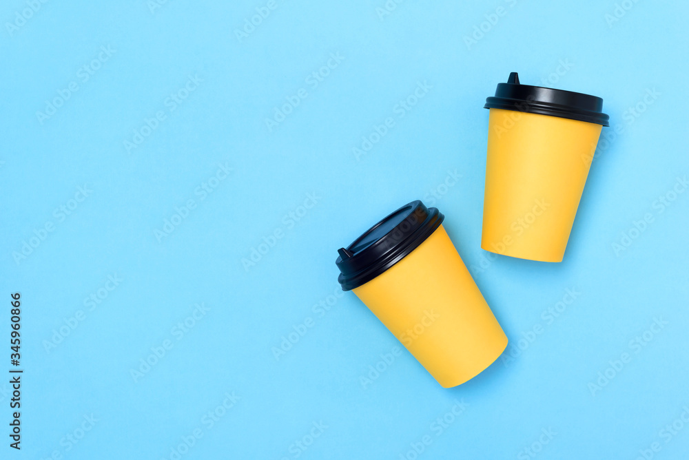 Yellow paper cups on a light blue background. Place for text on the ...