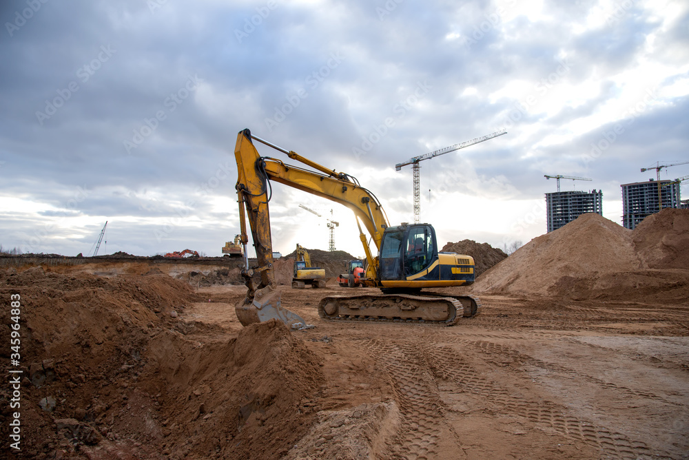 Excavator during earthmoving at construction site. Backhoe dig ground ...