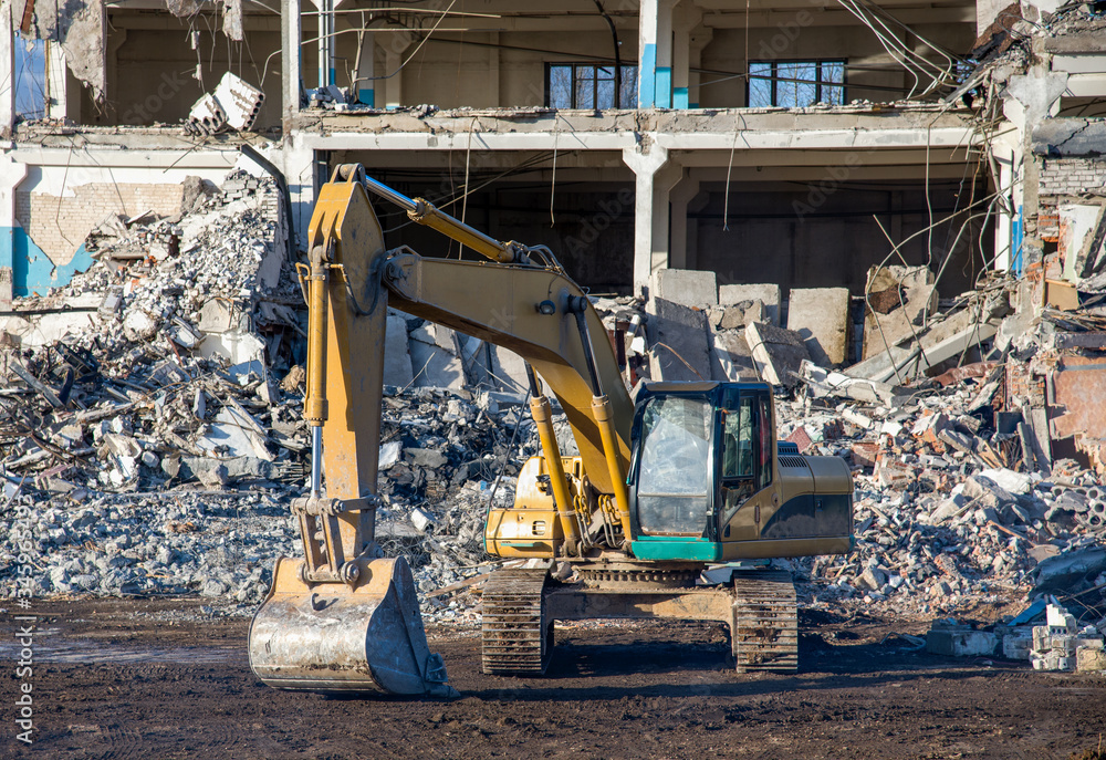 Yellow excavator with bucket at demolition of tall building. Hydraulic ...
