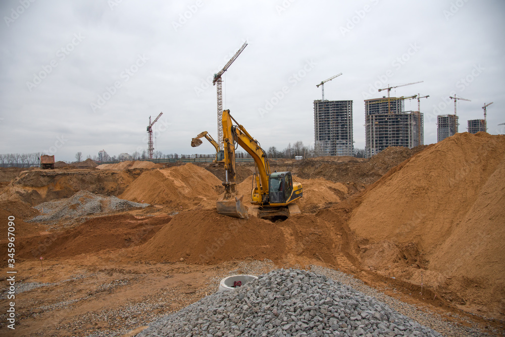 Excavators at earthworks on construction site. Backhoe loader digs a ...