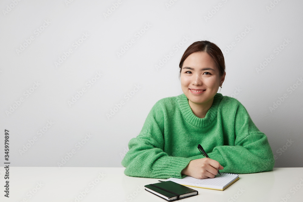Young asian woman taking down notes in diary wearing casual clothes ...