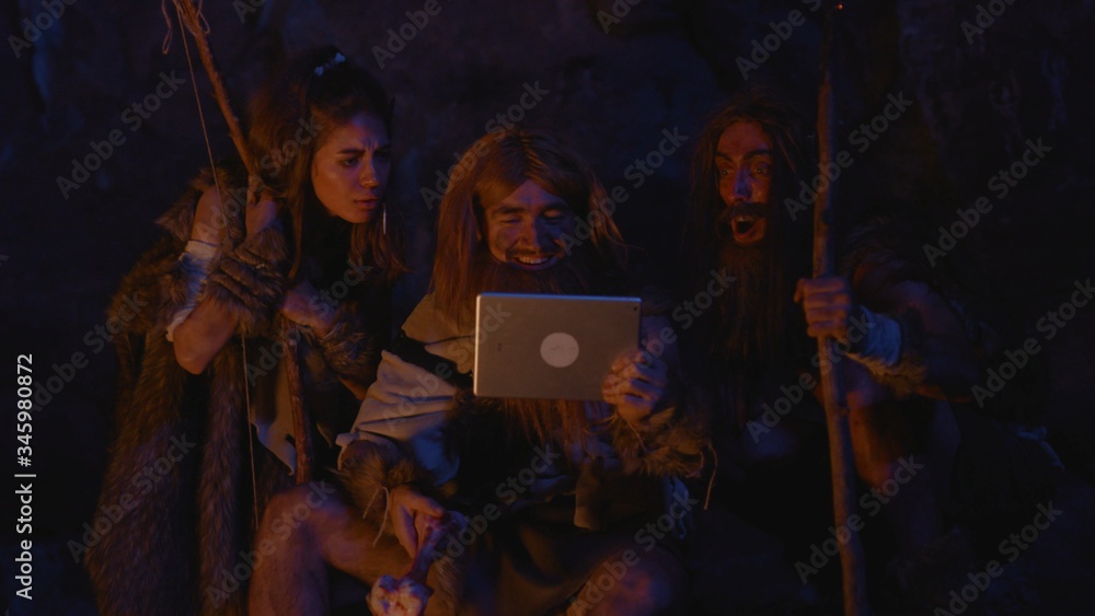 Prehistoric wild tribe leader eating raw meat and using mobile smart ...