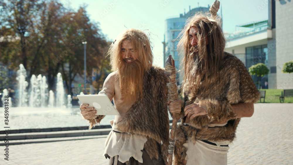 Backward primitive neanderthals using tablet pc in the street. Two ...