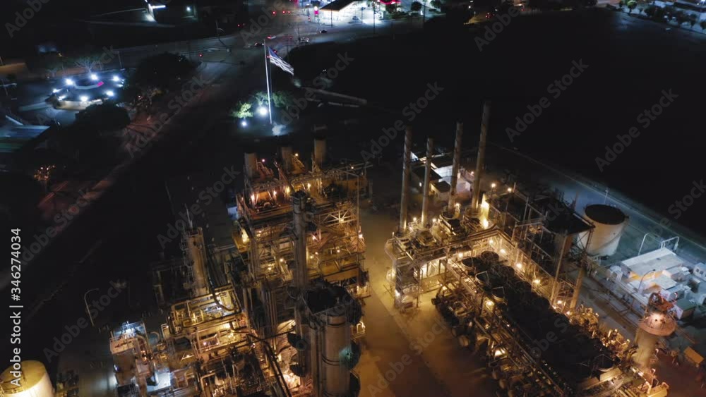 Aerial footage over the flickering at night petroleum refinery standing ...