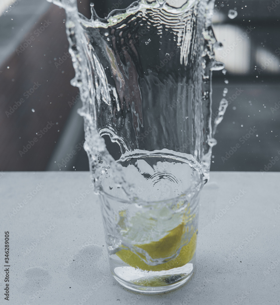 fotografía de un limón cayendo sobre un baso de agua. El agua salpica ...