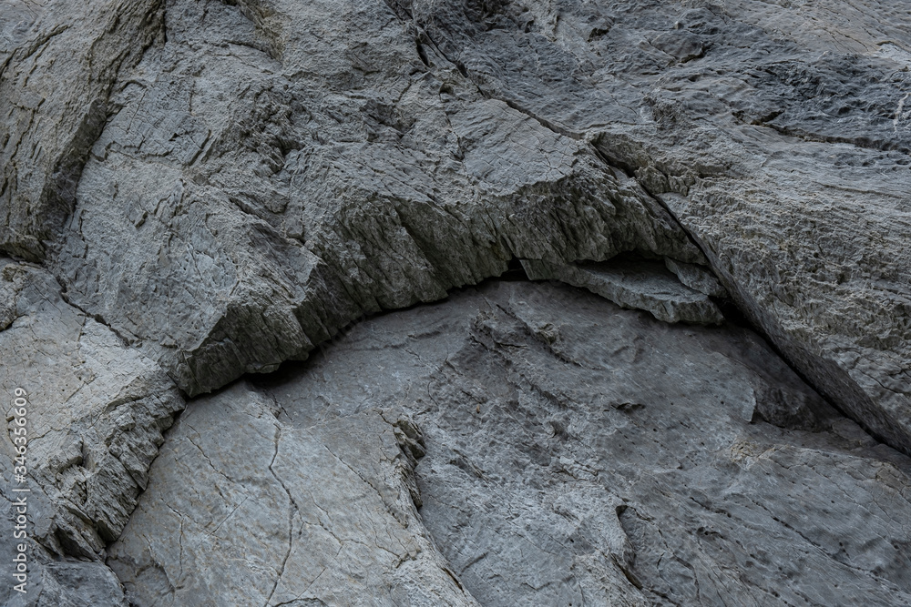 Aged shabby cliff face with divided by cracks layers. Rough gray stone ...
