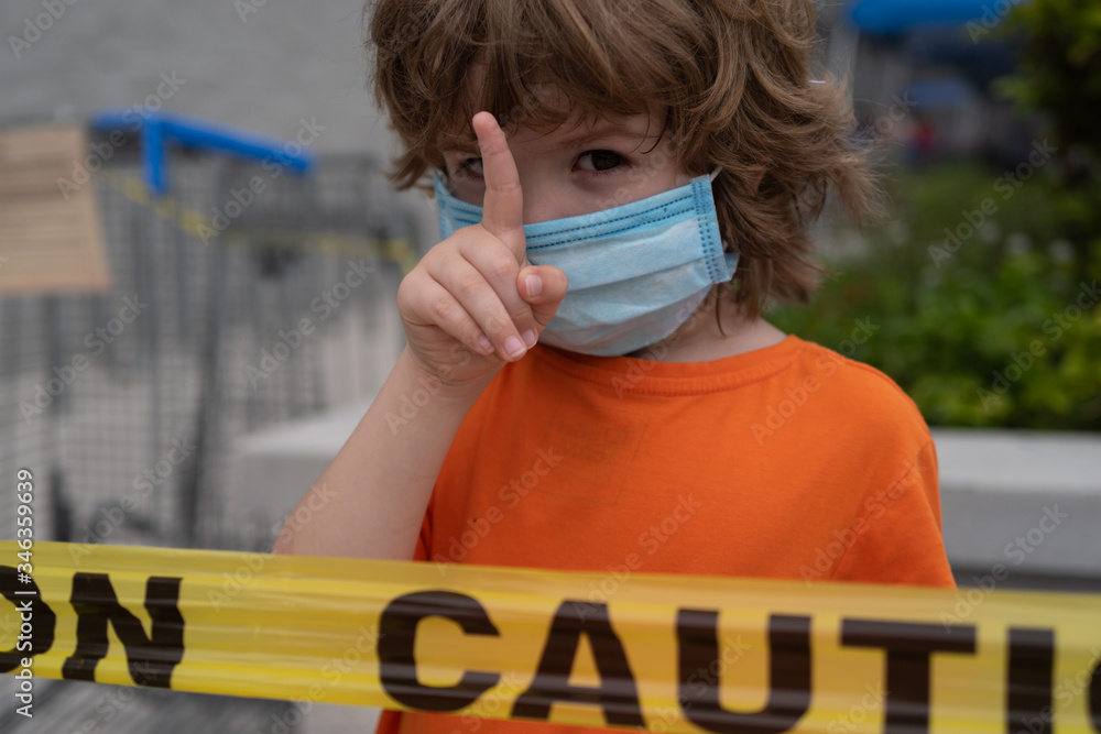 Warning. Cute child in the mask shows a warning sign during coronavirus ...