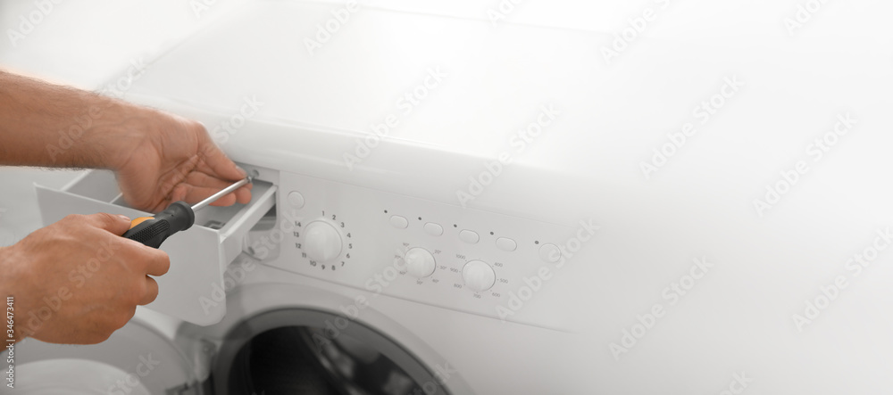 Professional plumber repairing broken washing machine, space for text ...