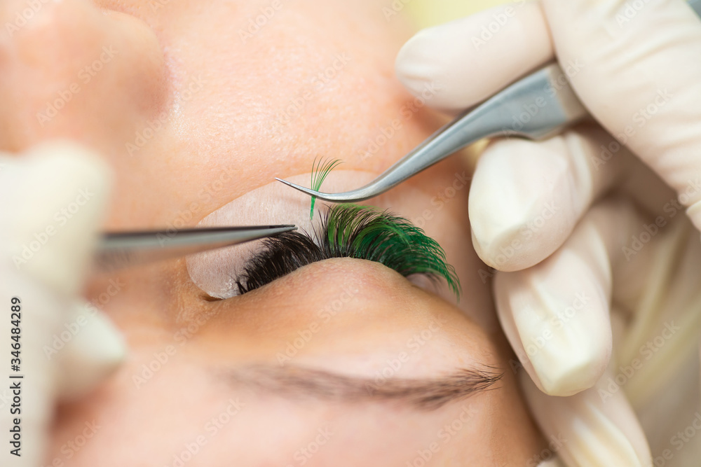 The master builds up large colored eyelashes to the client. Preparation ...