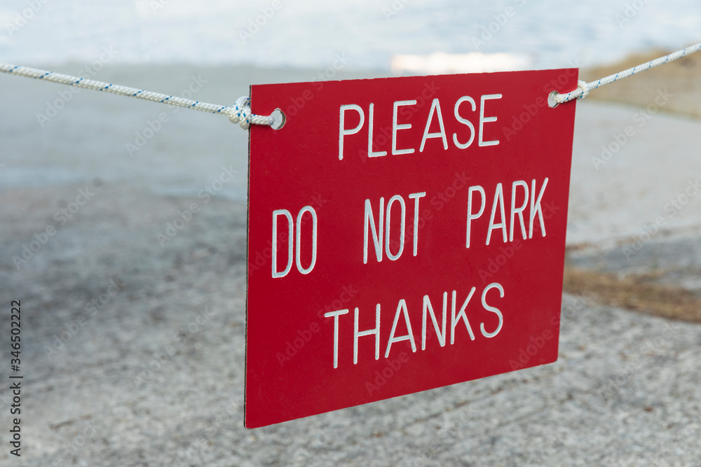 Red sign hanging on a cord saying please do not park thanks outside in ...