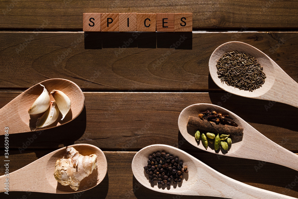 Spices on wooden spoons. Cooking/food related background with various spices and herbs, top ...