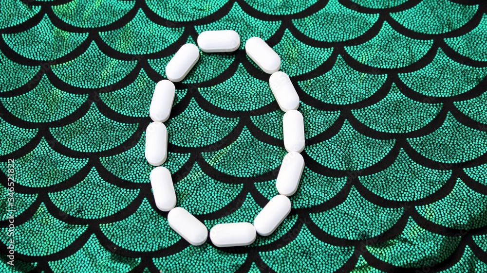 Alphabet made of pills on a green and black background. Vitamins on a ...