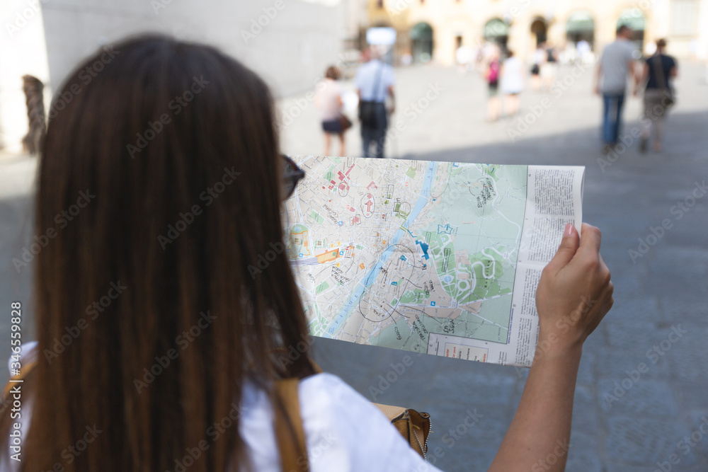 Young woman looking a map and some handwritten notes on it to get to ...