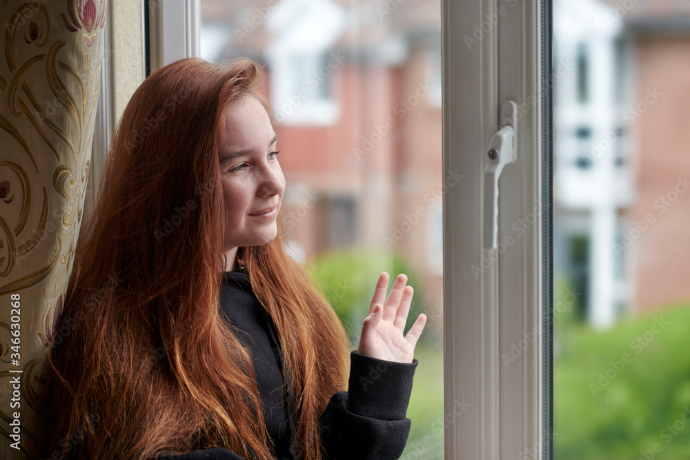 Smiling teenage girl looking out window and waving hand Stock Photo ...