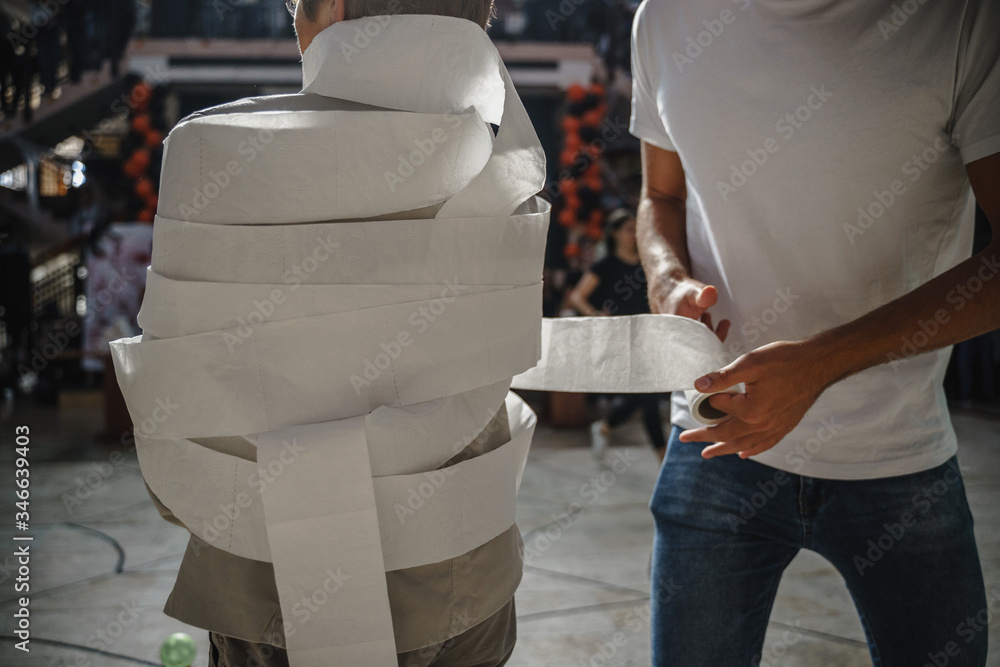 Short old woman being wrapped in toilet paper in a Halloweeen Game by a ...