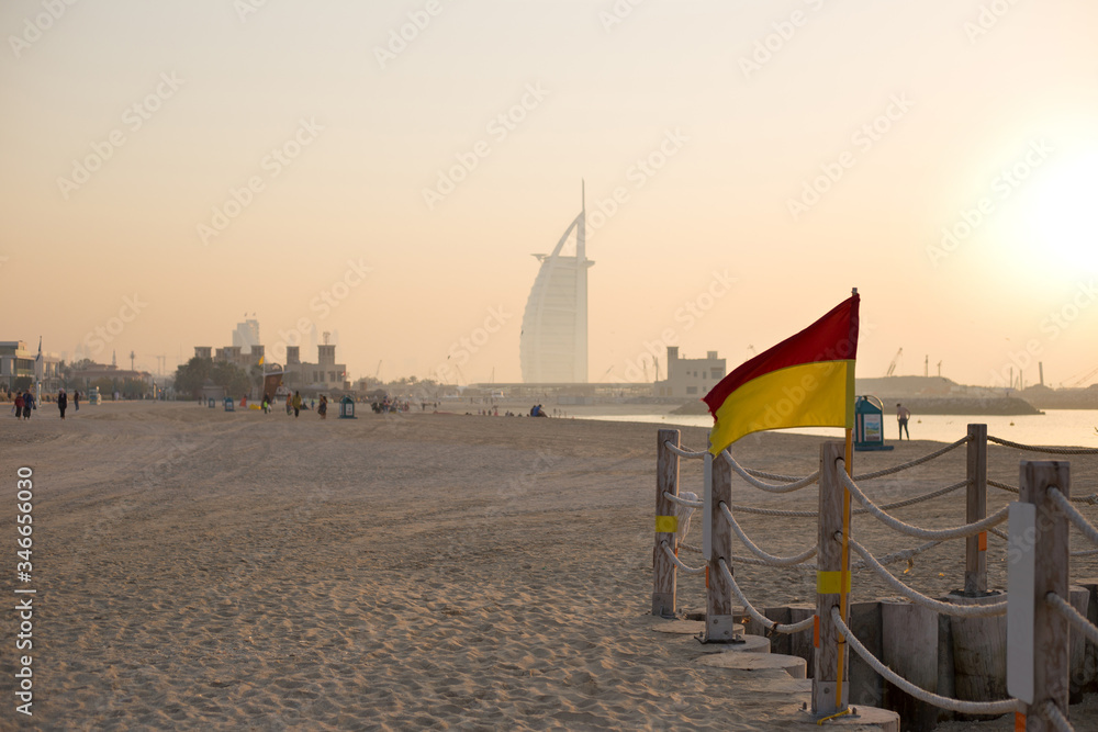 UAE flag on the sunset beach background in Dubai. Emirates flag on the ...