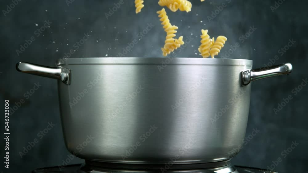 Throwing pasta fusilli into boiled water in pot, shooting with high ...