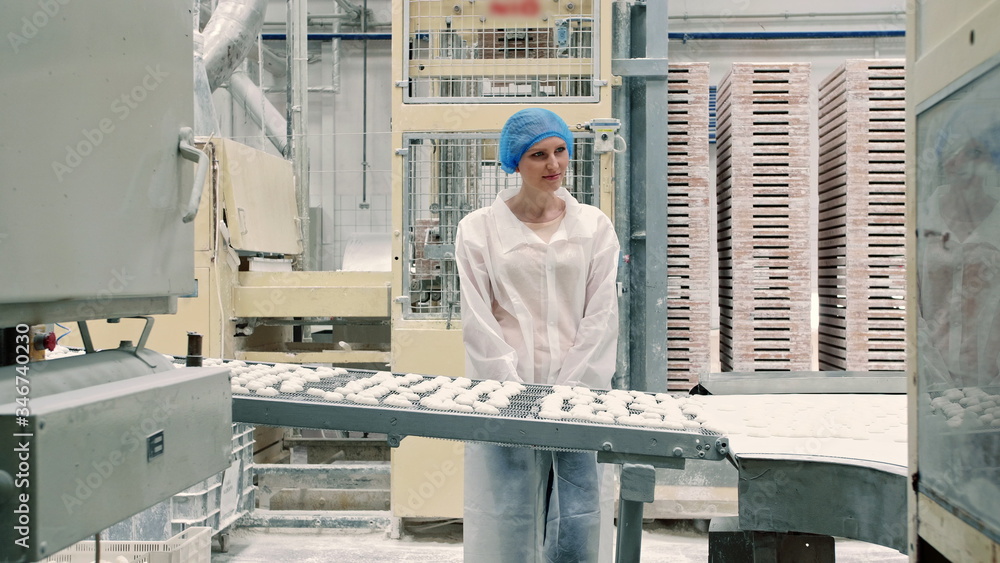 Candy factory. Controller checking conveyor with candies. Young woman ...