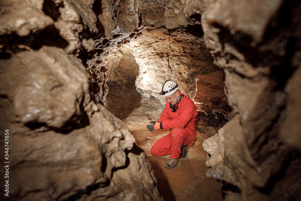 Man walking and exploring dark cave with light headlamp underground ...