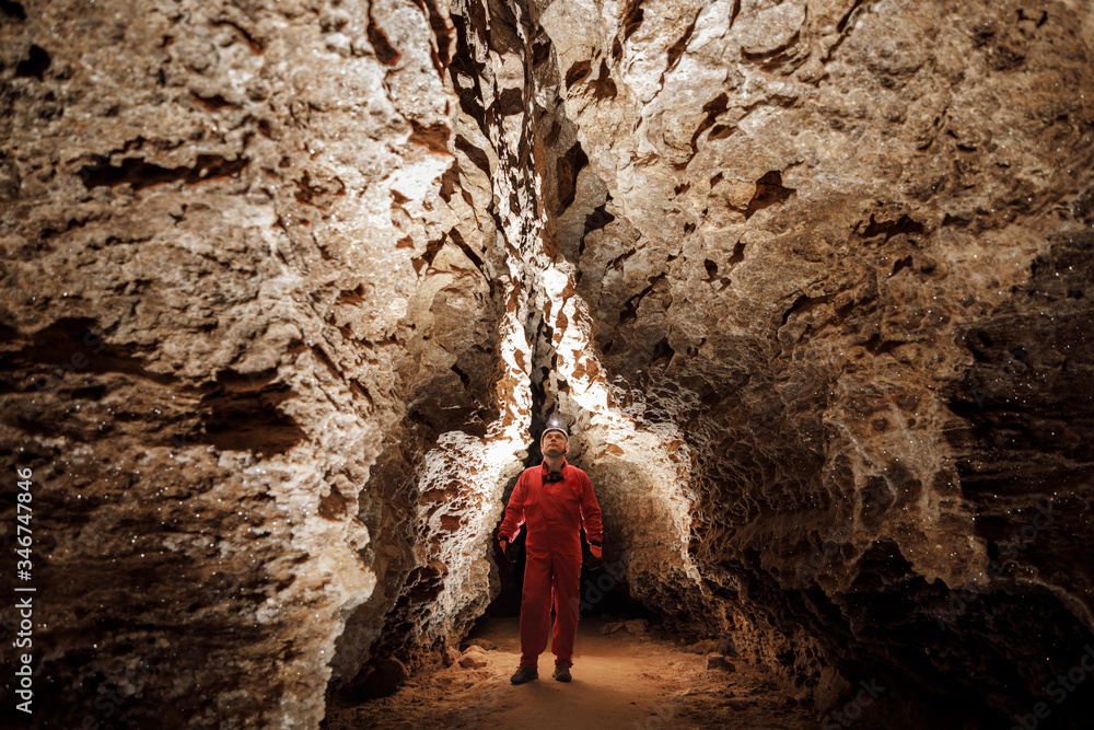 Man walking and exploring dark cave with light headlamp underground ...