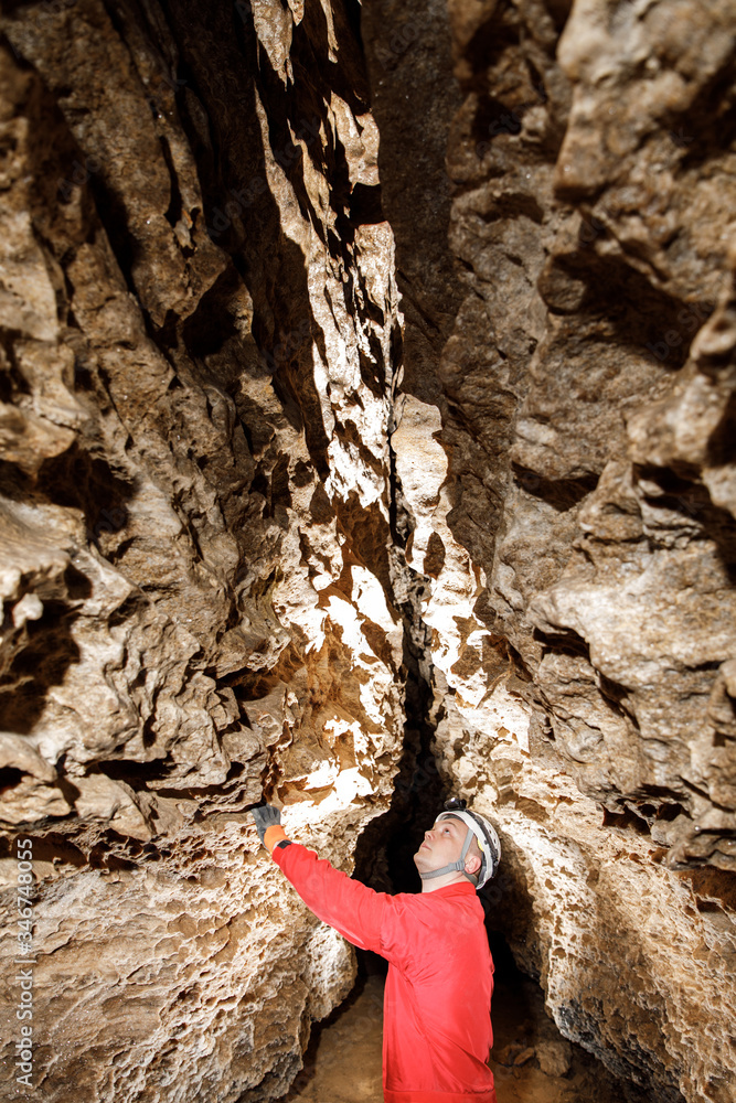 Man walking and exploring dark cave with light headlamp underground ...