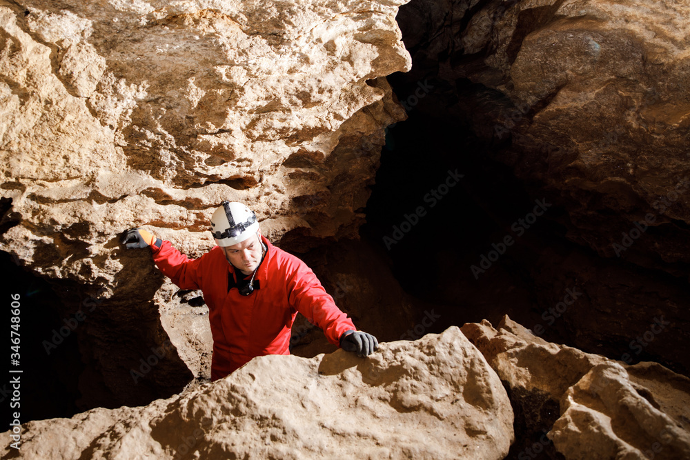 Man walking and exploring dark cave with light headlamp underground ...