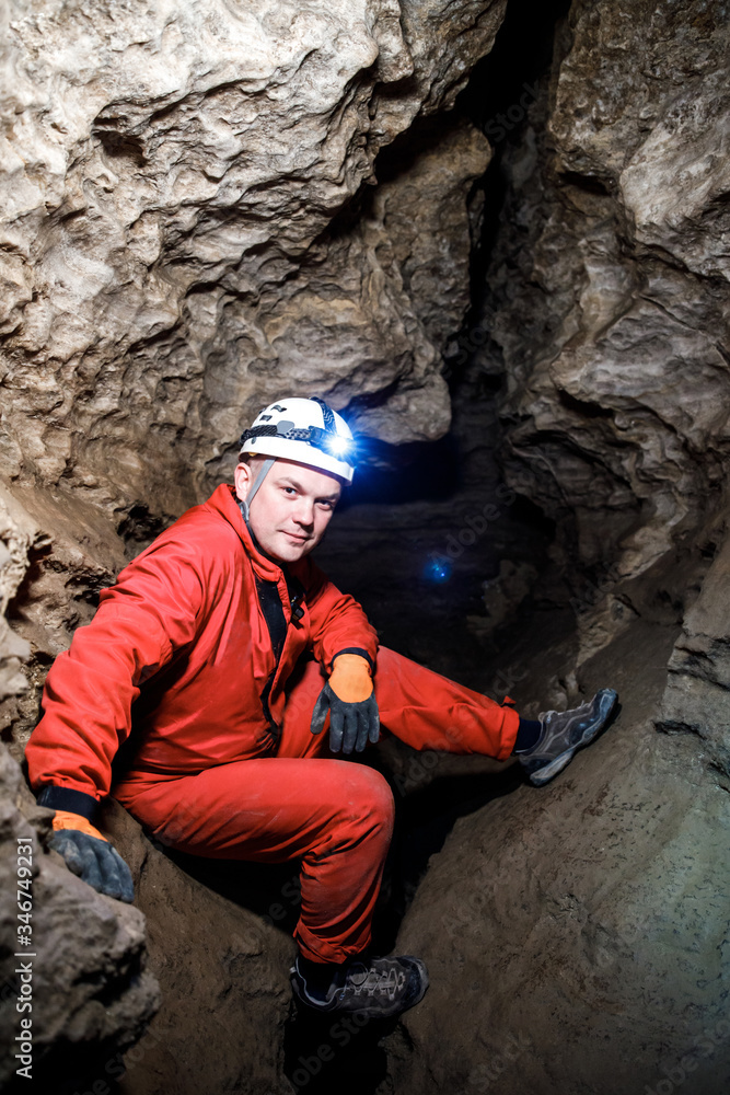 Man walking and exploring dark cave with light headlamp underground ...