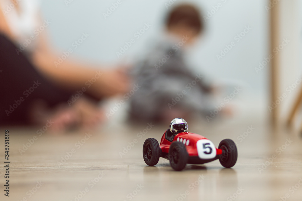 Red toy racing car with number five plate isolated on a hardwood floor ...