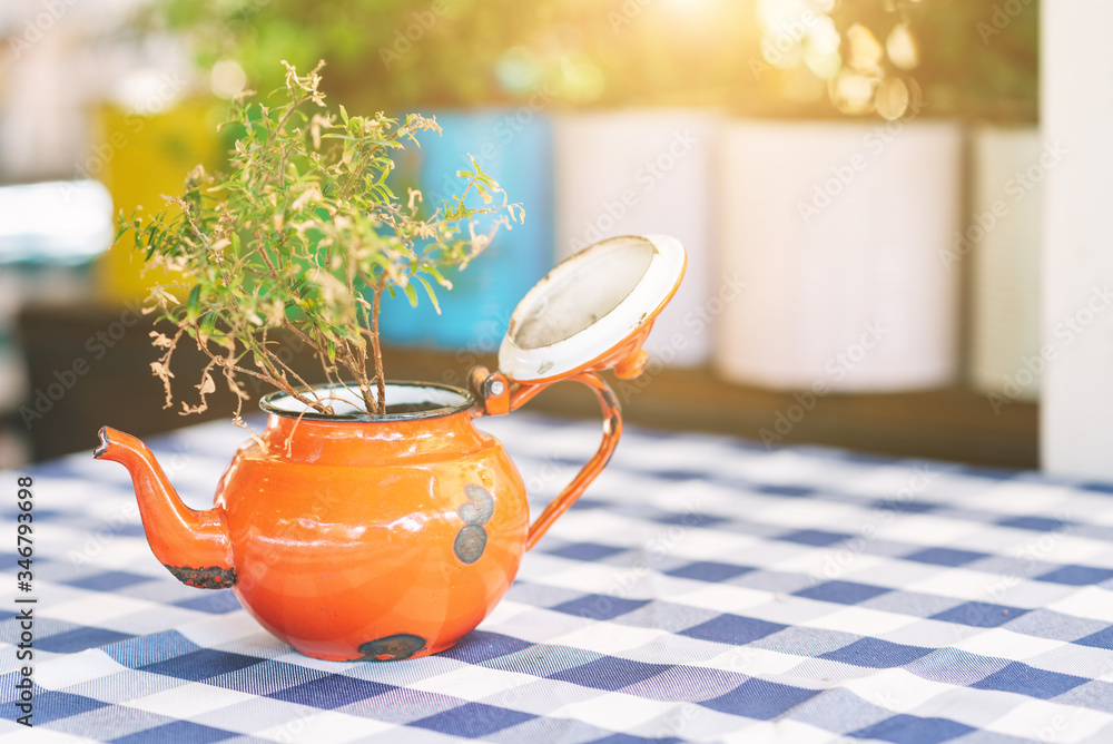 Old teapot repurposed as a vase for bouquet on table,warm light of ...