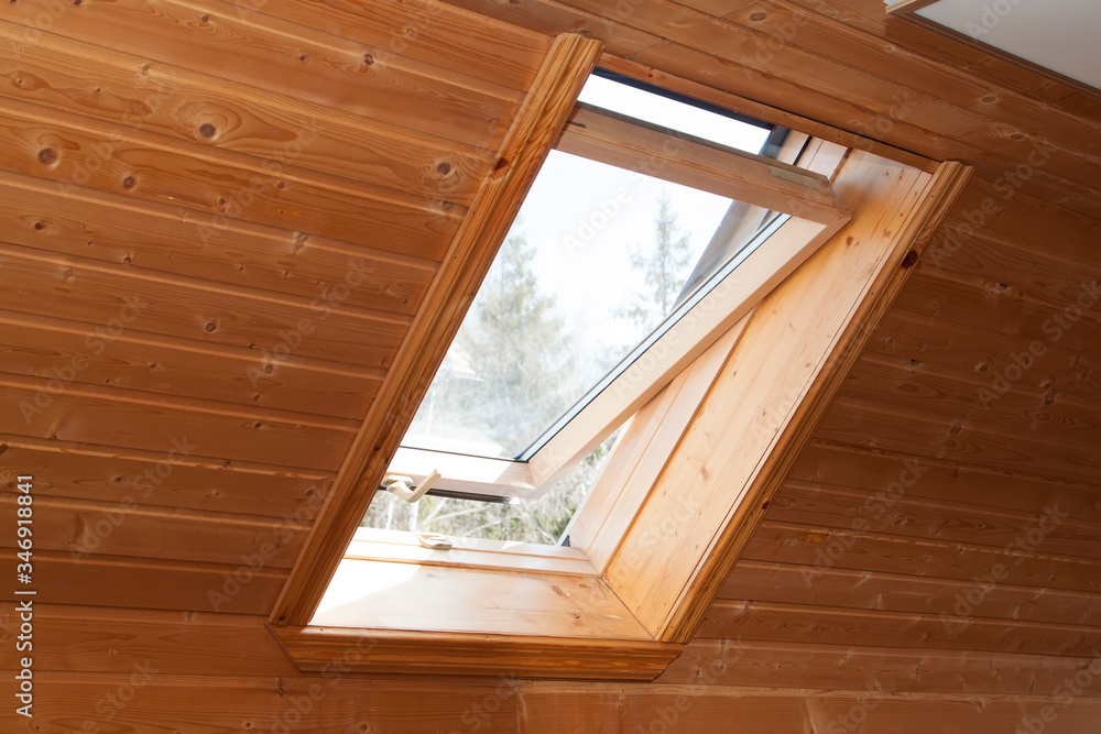 Open dormer window in wooden house in the attic. Room has sloping ...