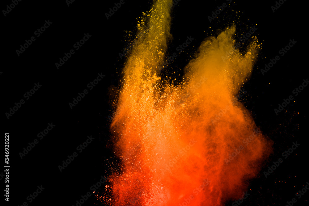 orange powder explosion isolated on black background.Colored dust ...