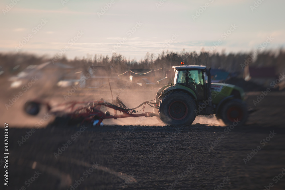 Tractor with a disc harrow system harrows the cultivated farm field ...