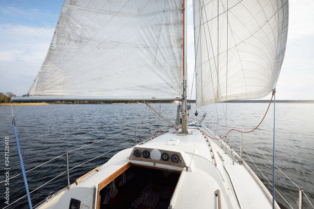 White yacht with full sails running downwind wing-on-wing, sailing ...