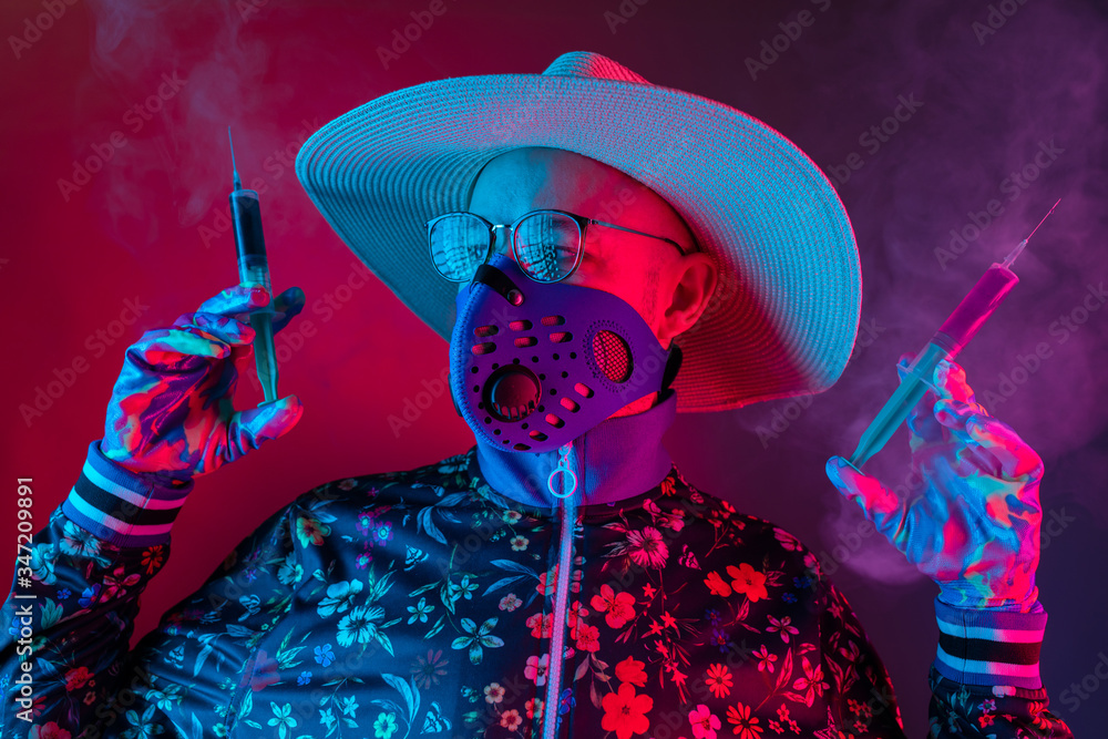Strange man in medical respirator mask, glasses and hat holding two ...