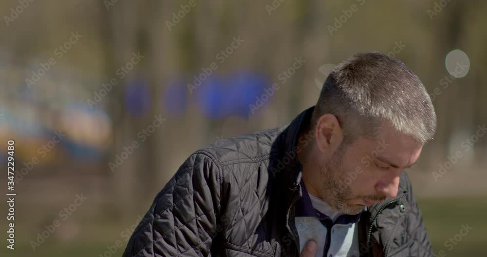 Portrait of an adult male suffering from a coughing fit on the street ...