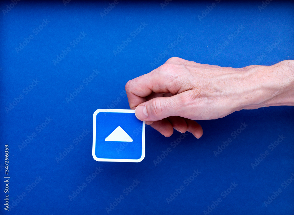 main qui tient une illustration de flèche vers le haut sur fond bleu ...
