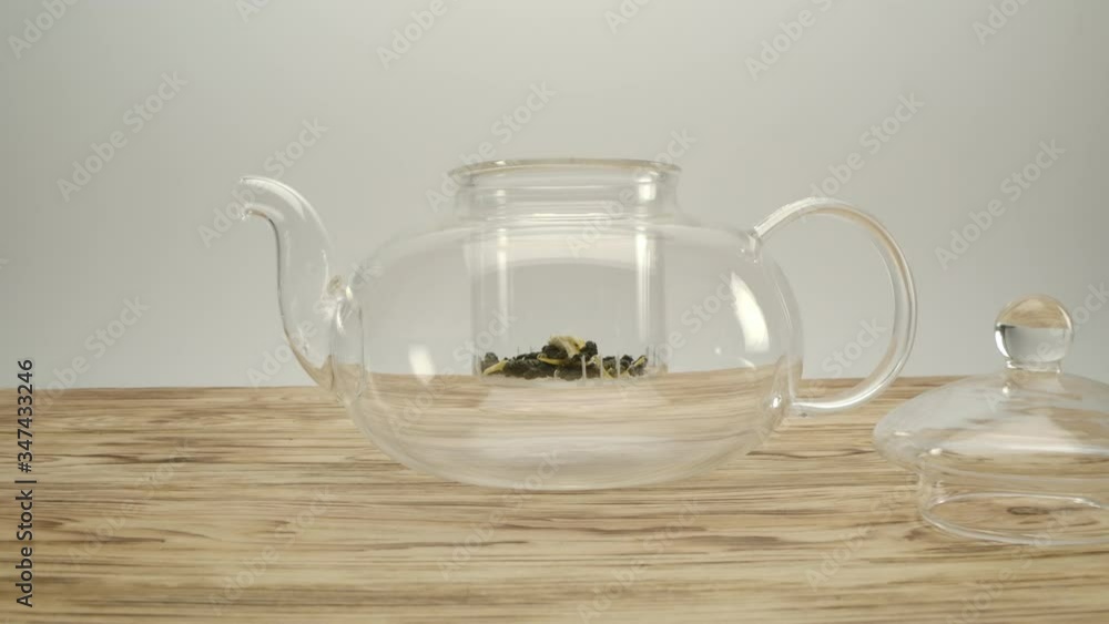 Sprinkling dry white authentic tea into a transparent teapot. Slow ...