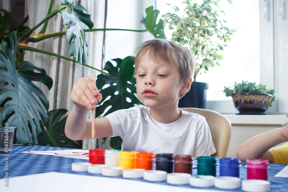 Happy cheerful child drawing with brush, in home interior during ...