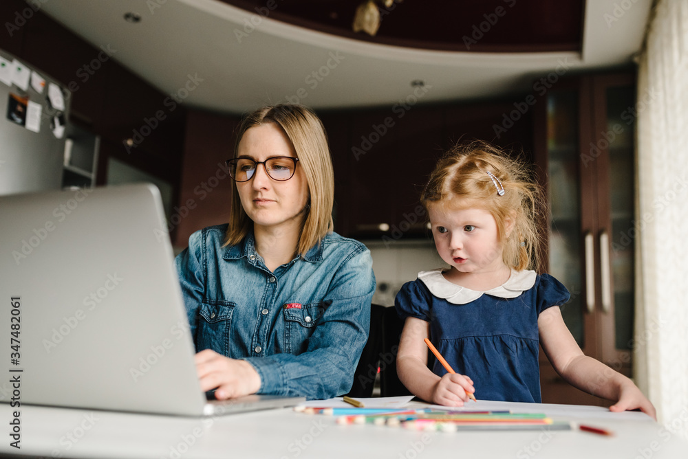 Stay at home mom working remotely on laptop computer while taking care ...