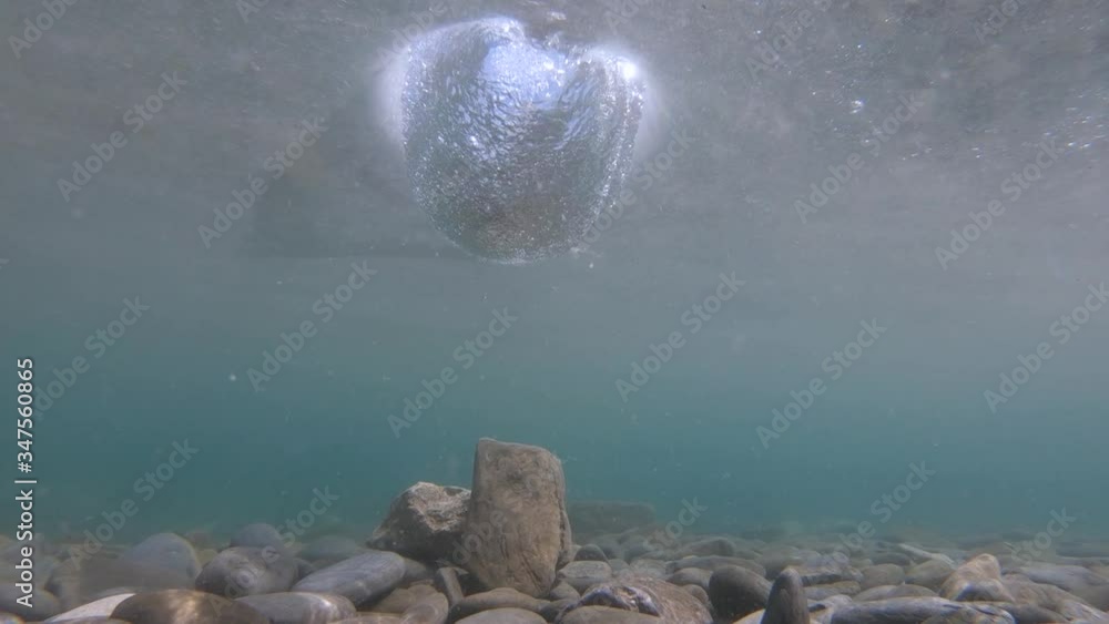 Slow motion underwater view of sea bottom. Shock wave visible on water ...