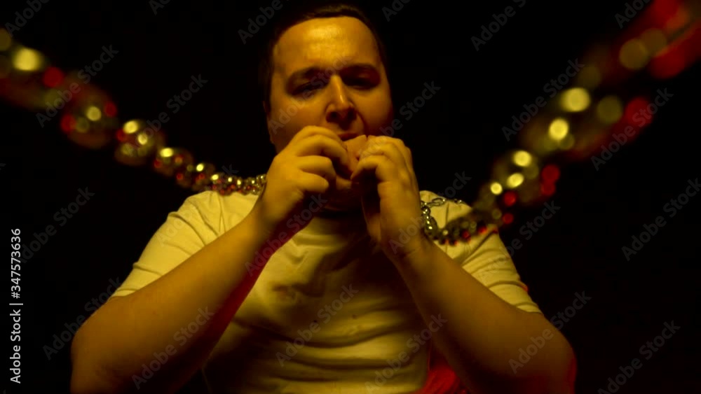 Fat man eating fast food whose chains are on his neck. Hostage concept ...