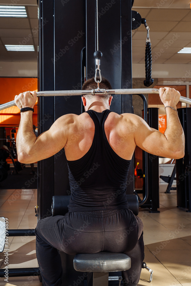 Shoulder pull down machine. Fitness man working out lat pulldown ...